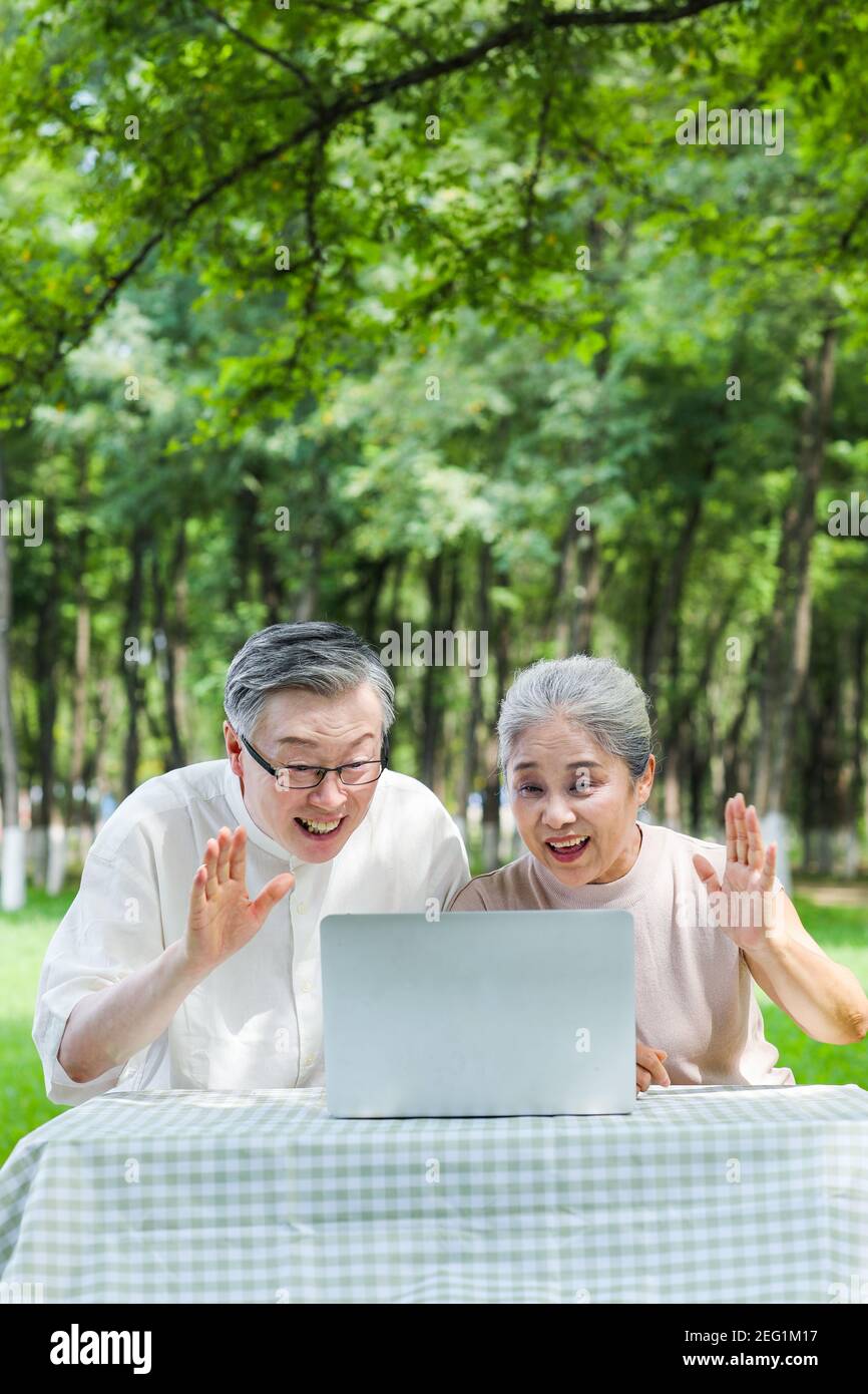 Elderly couples use computer video chat waving Stock Photo - Alamy