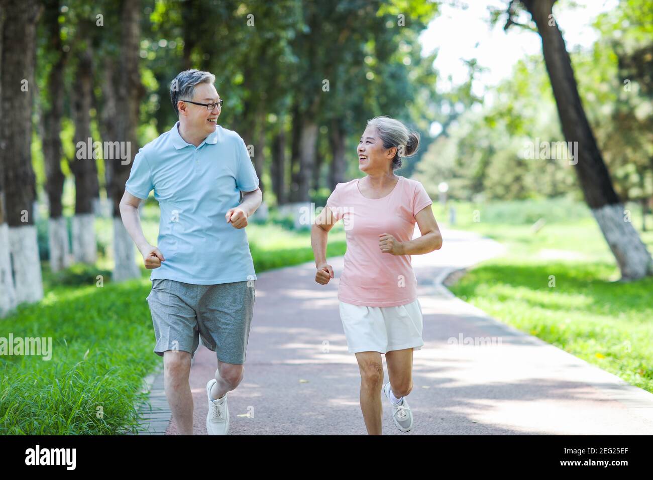 Old couple jogging in outdoor park smiling Stock Photo - Alamy