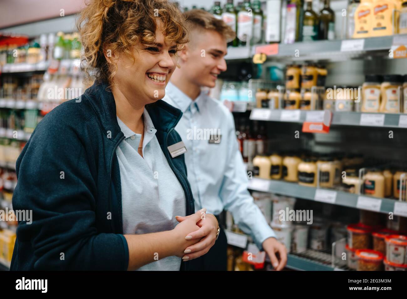Grocery store manager walking with male employee and smiling. Woman ...