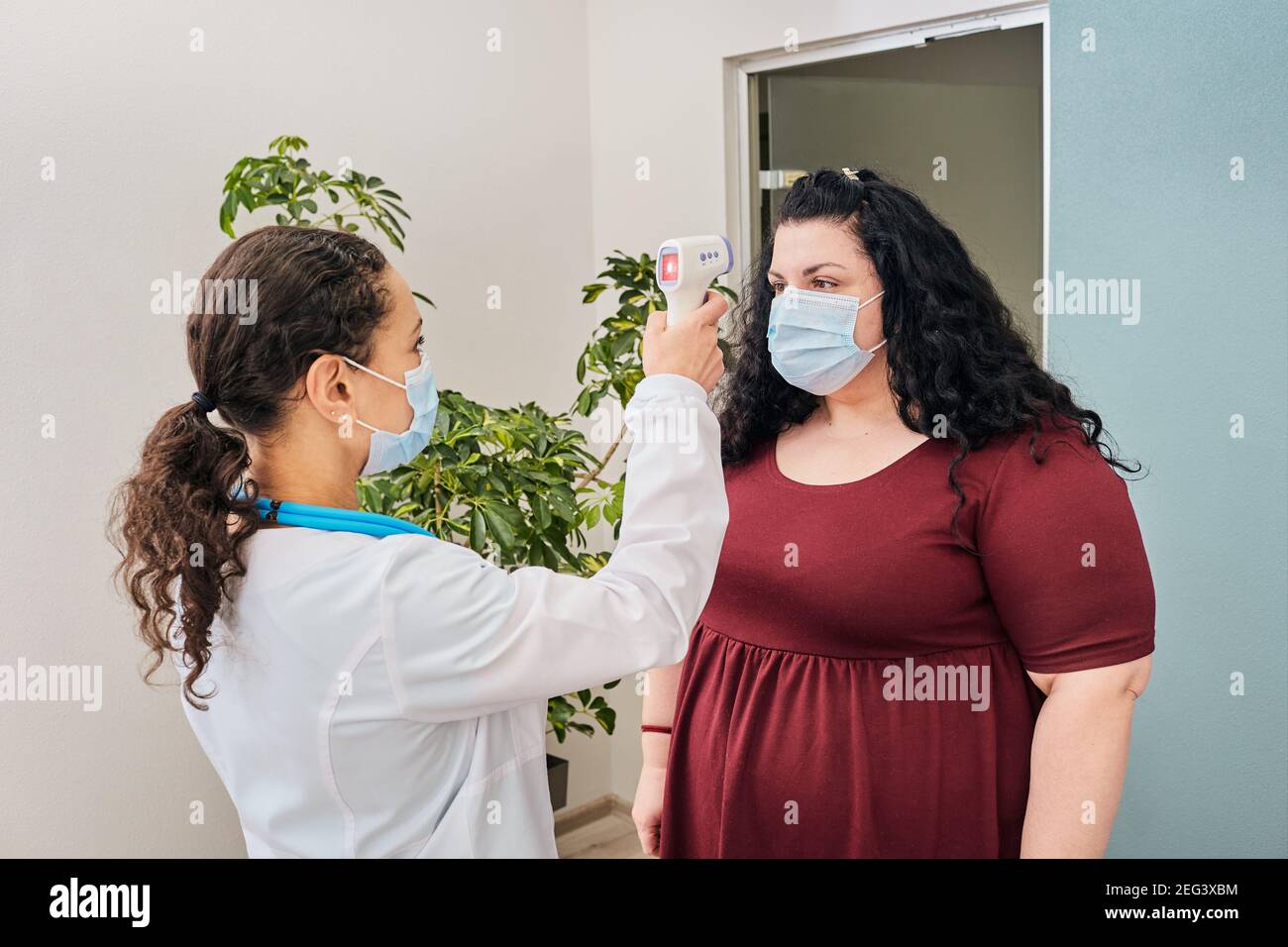 doctor checking woman's body temperature with a non-contact thermometer ...