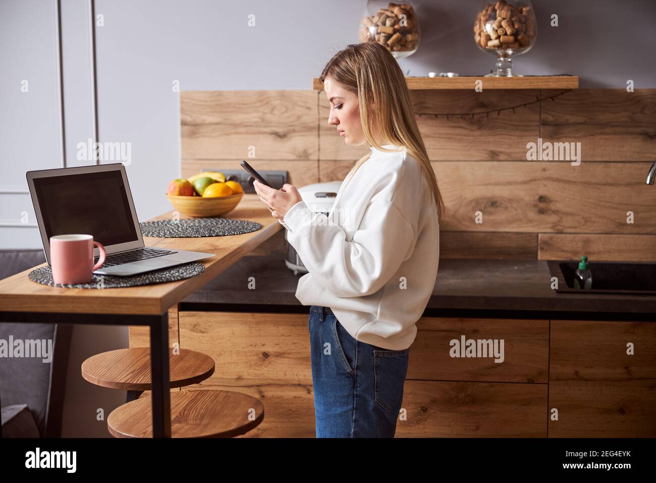Female standing near the table and using smartphone Stock Photo - Alamy