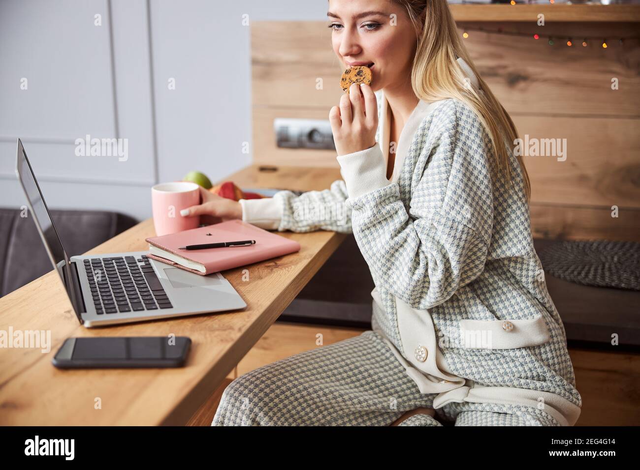 Woman biting a chocolate cookie while holding teacup Stock Photo - Alamy