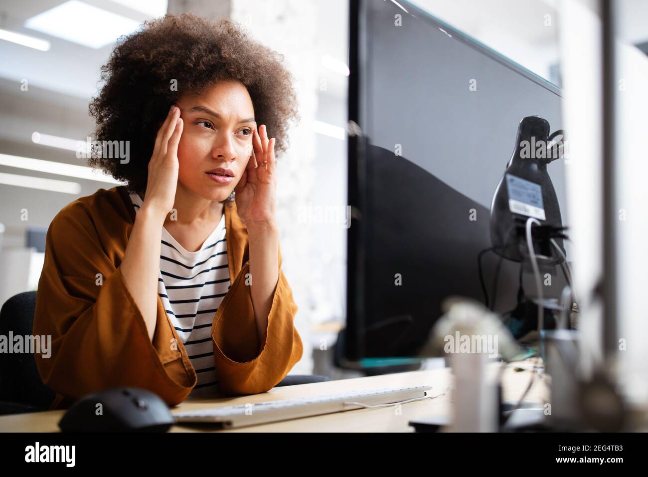 Overworked and frustrated young woman in front of computer in office ...