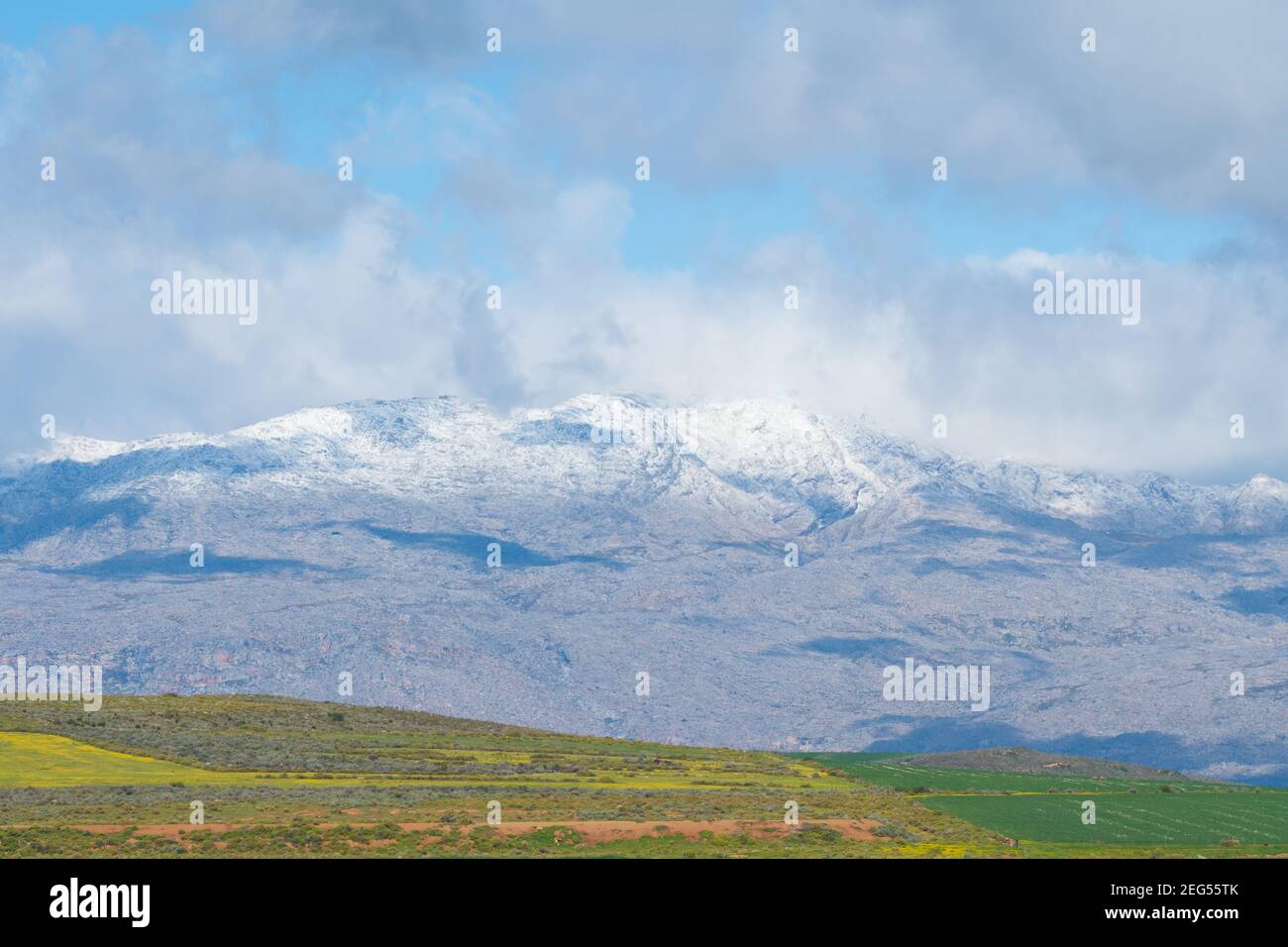 view onto an agricultural landscape of snow capped mountains and fields ...