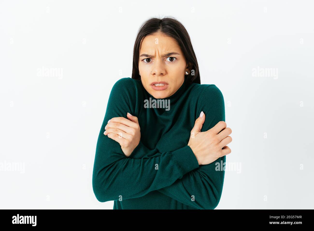 Young woman feeling cold and hugging herself with both arms to keep ...