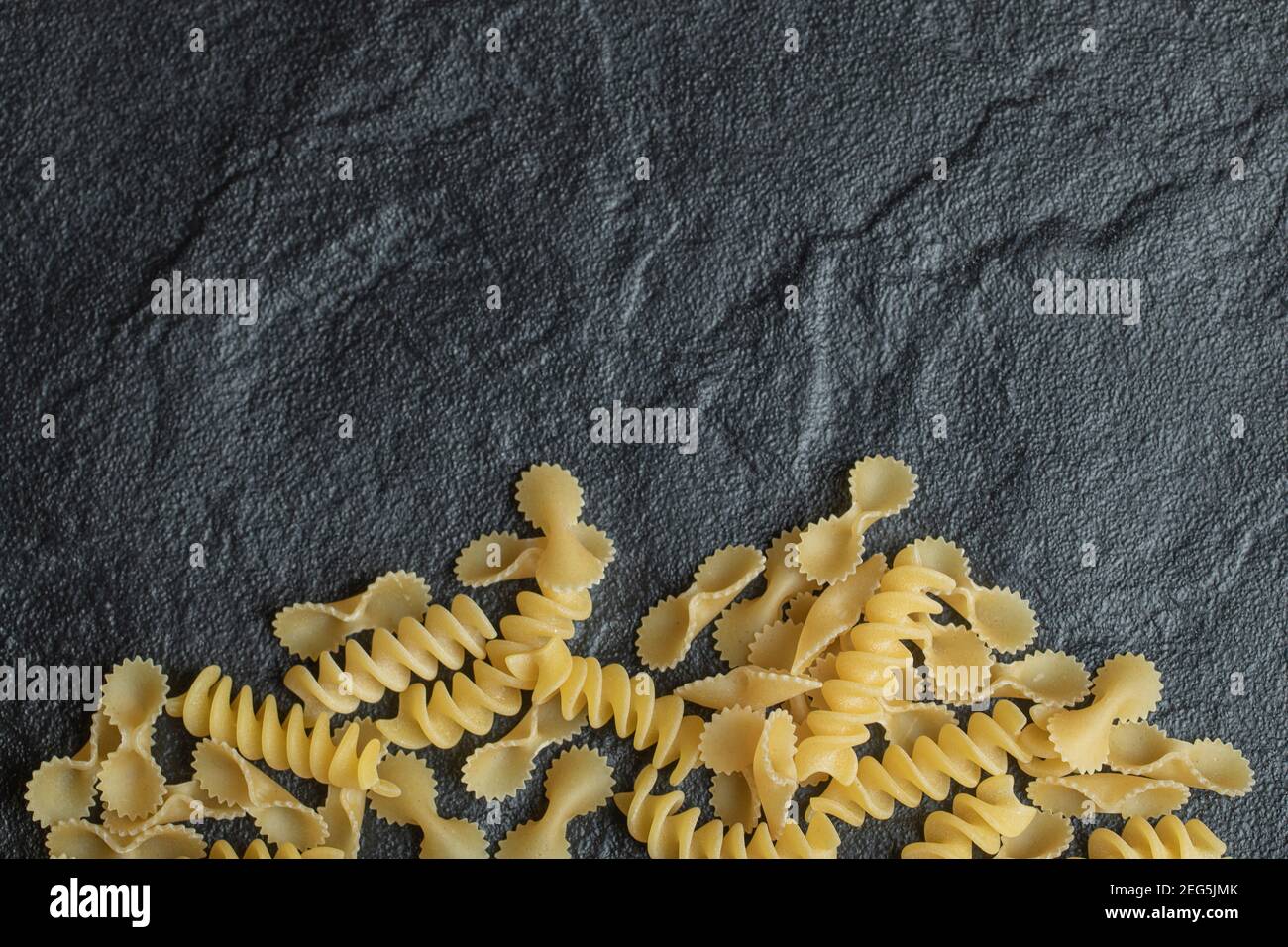Uncooked spiral macaroni on a dark background Stock Photo - Alamy