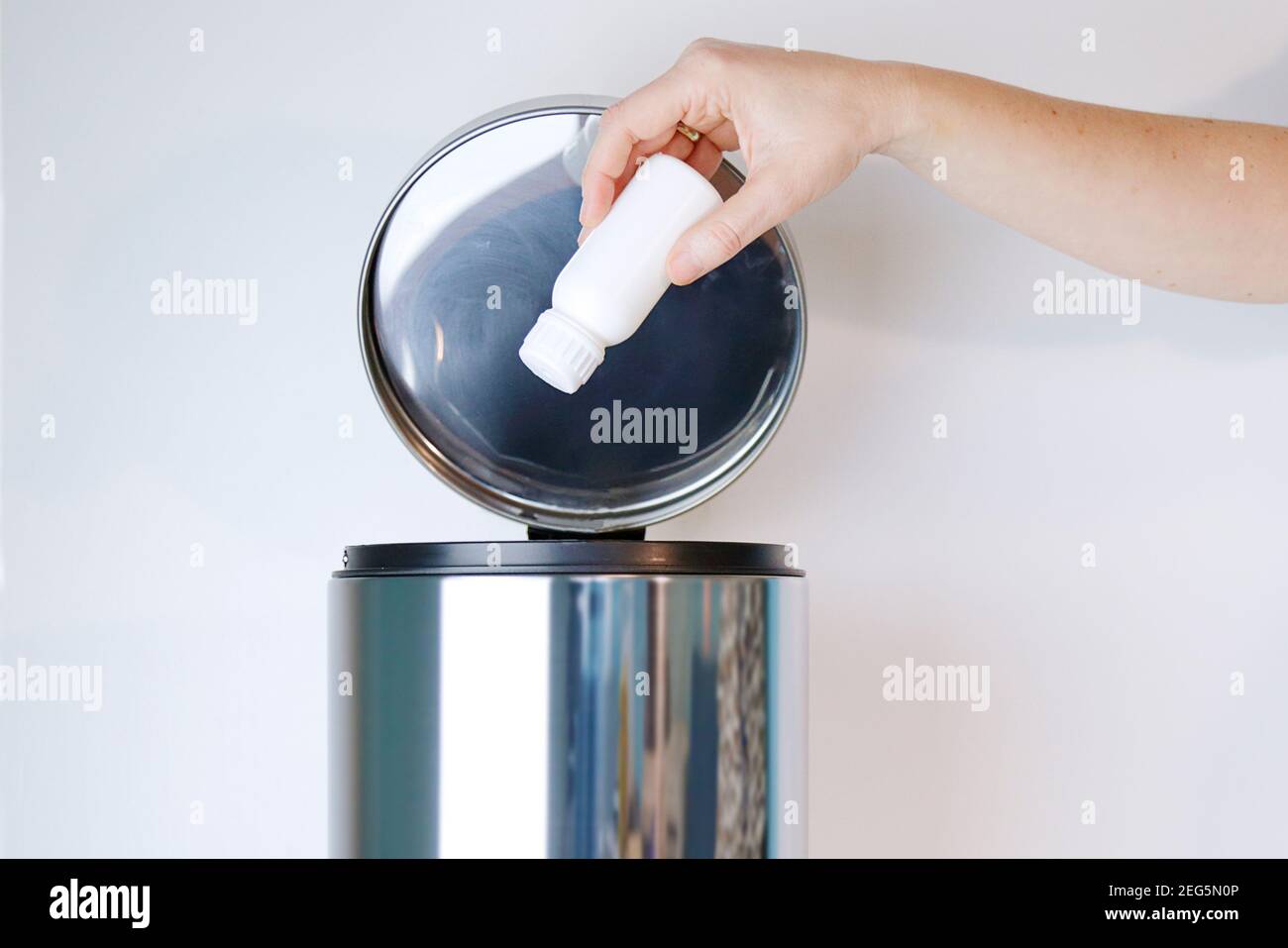 Woman hand recycling a plastic container into the garbage bin against ...