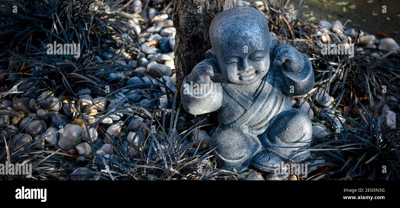 Stone buddhist monk statue in a garden using hand action to close the ...