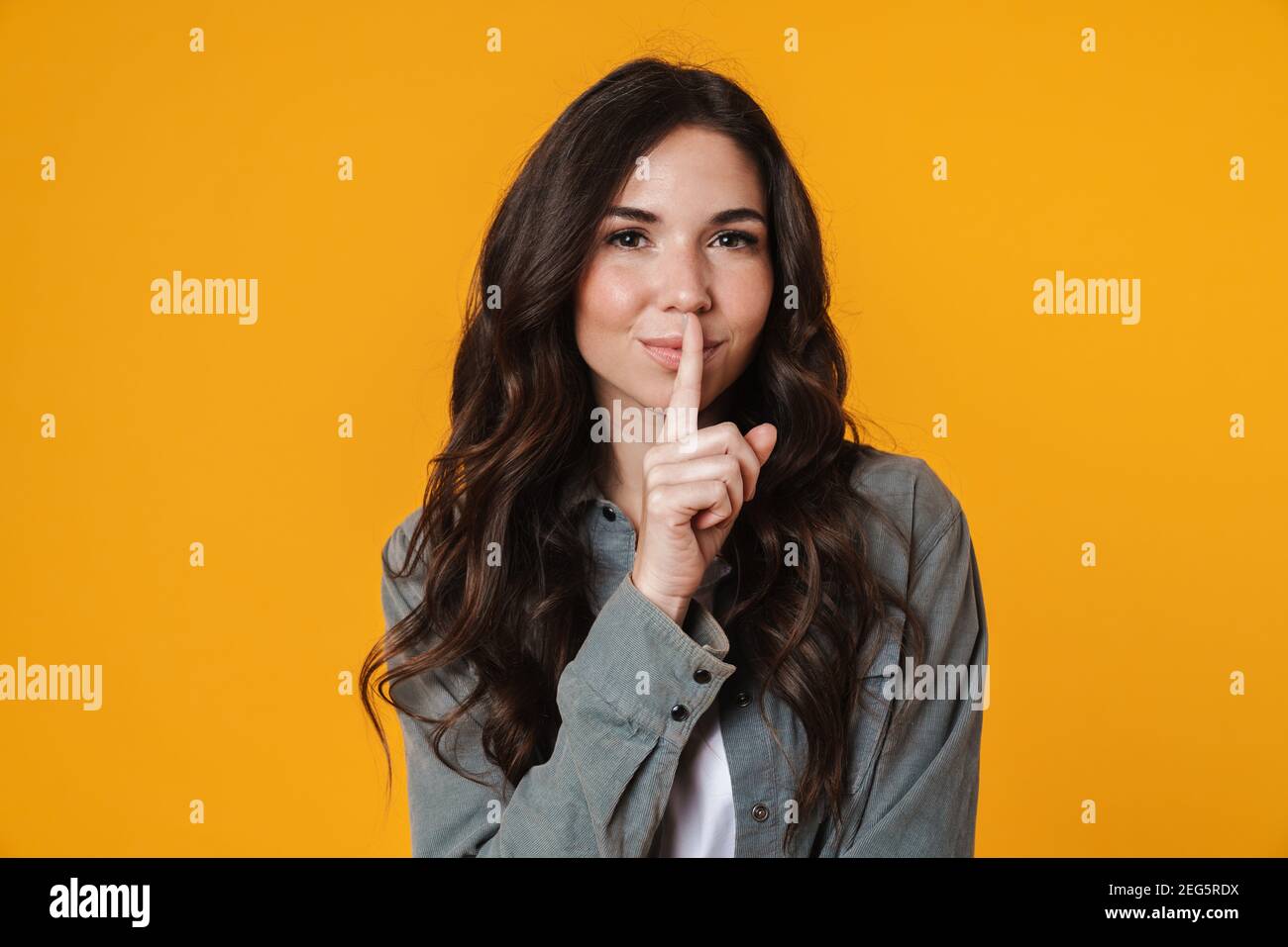 Pleased beautiful girl showing silence gesture on camera isolated over ...