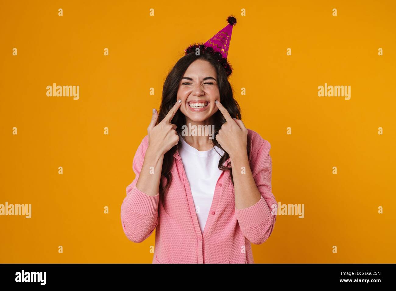 Happy nice girl smiling and pointing fingers at her cheeks isolated ...