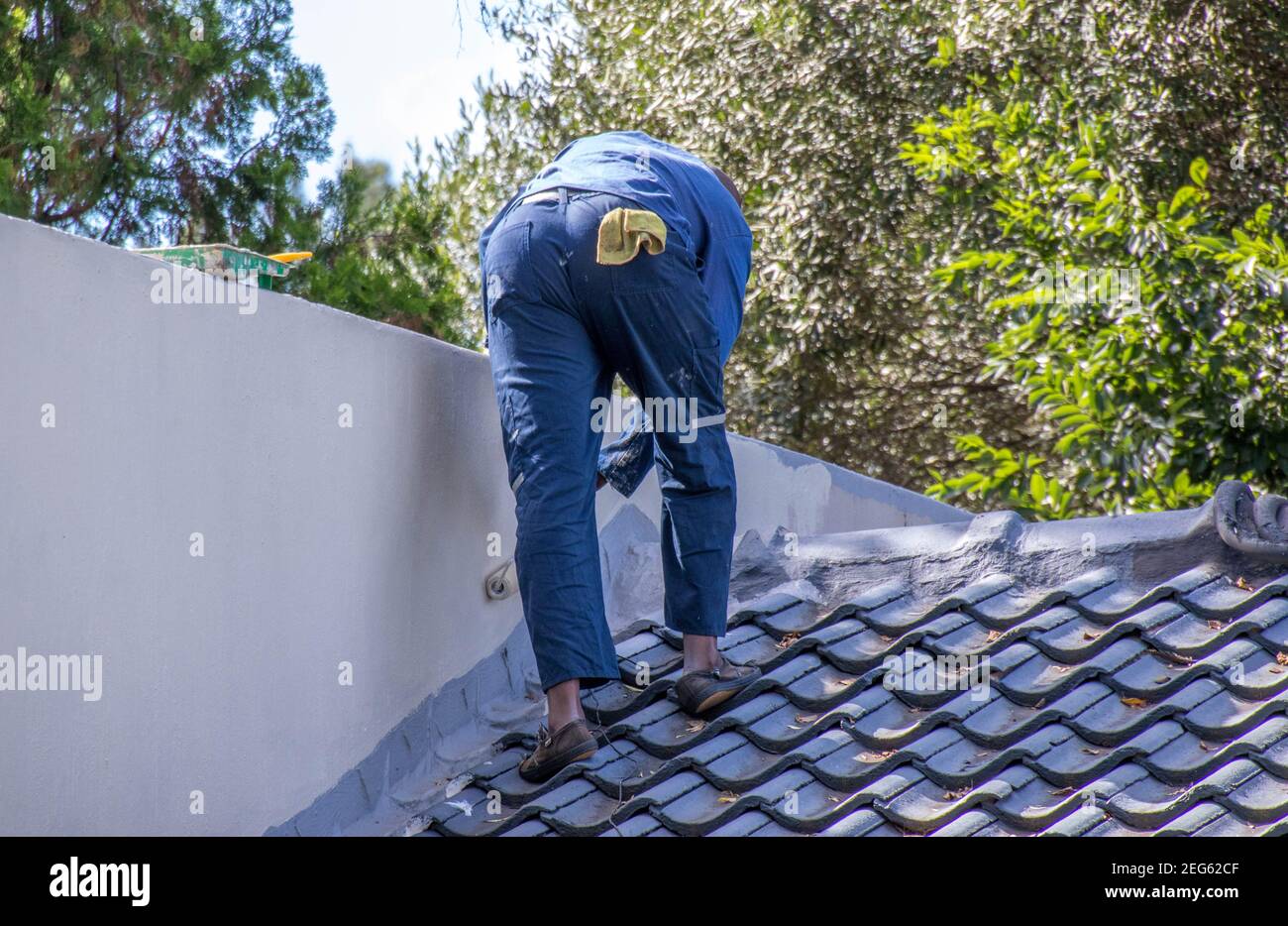 Johannesburg, South Africa - an unknown handyman painting on the roof ...