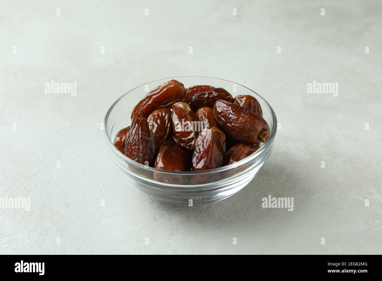 Glass bowl of dates on white textured background Stock Photo - Alamy