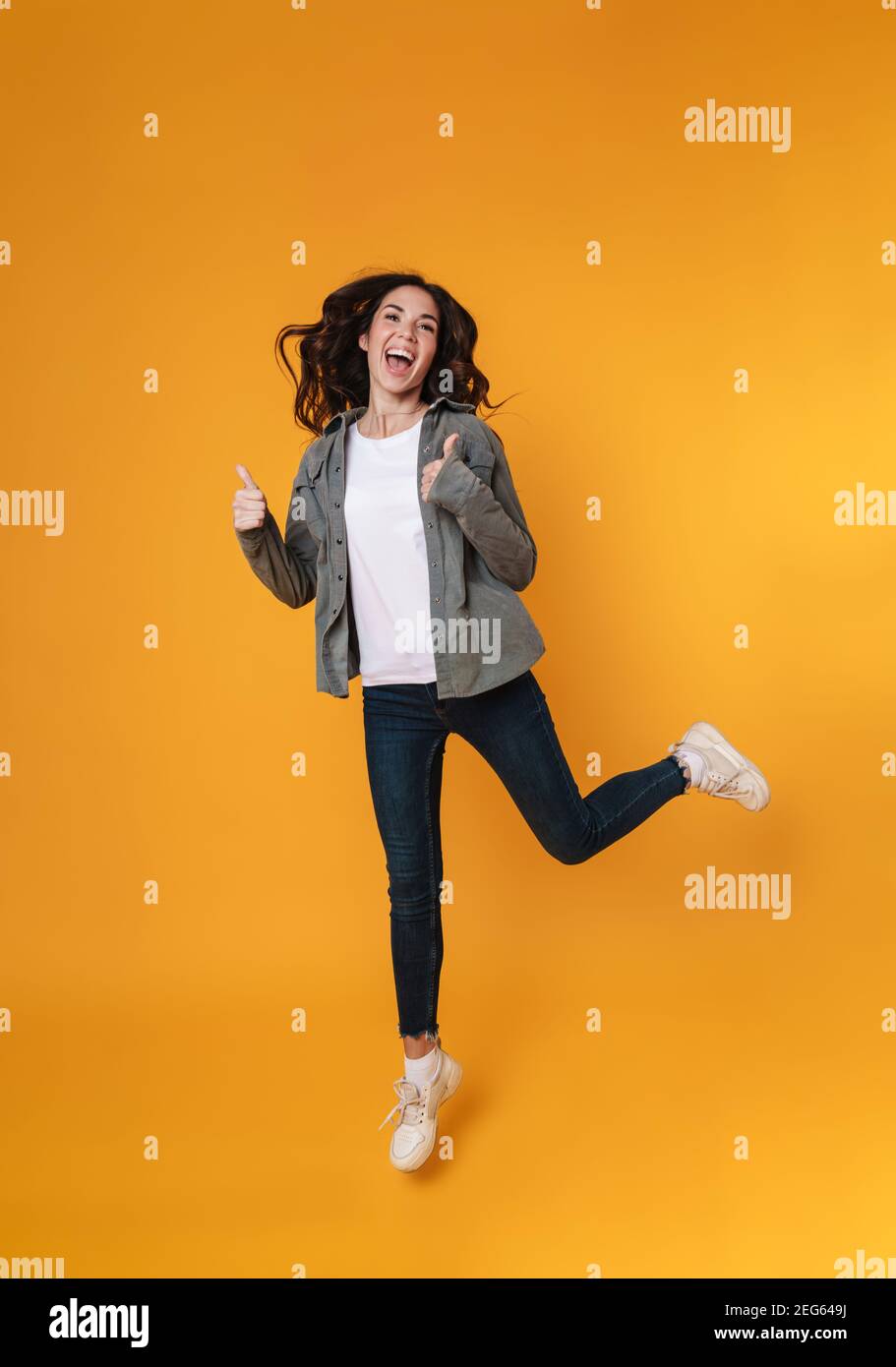 Excited beautiful girl showing thumbs up while jumping isolated over ...