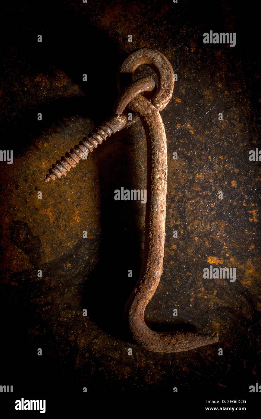 Rusty metal hook and screw on a weathered surface highlighting ...