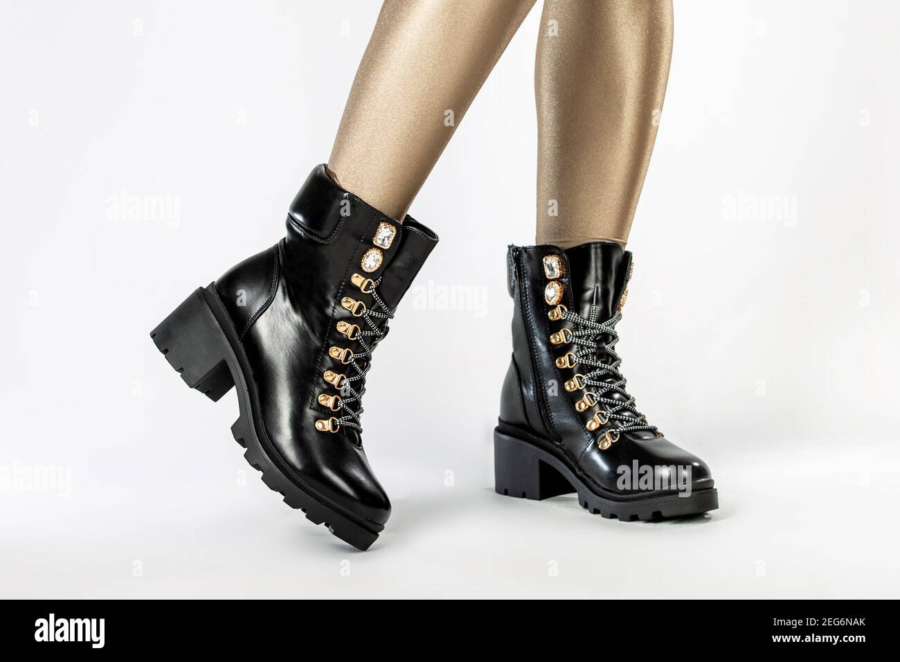 Female model wearing black boots in a studio against a white background ...