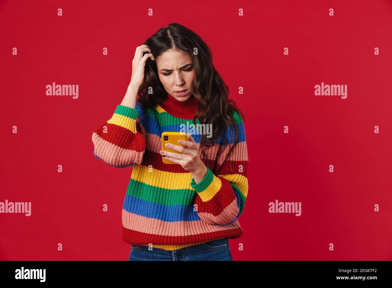 Brooding beautiful caucasian girl using mobile phone isolated over red ...