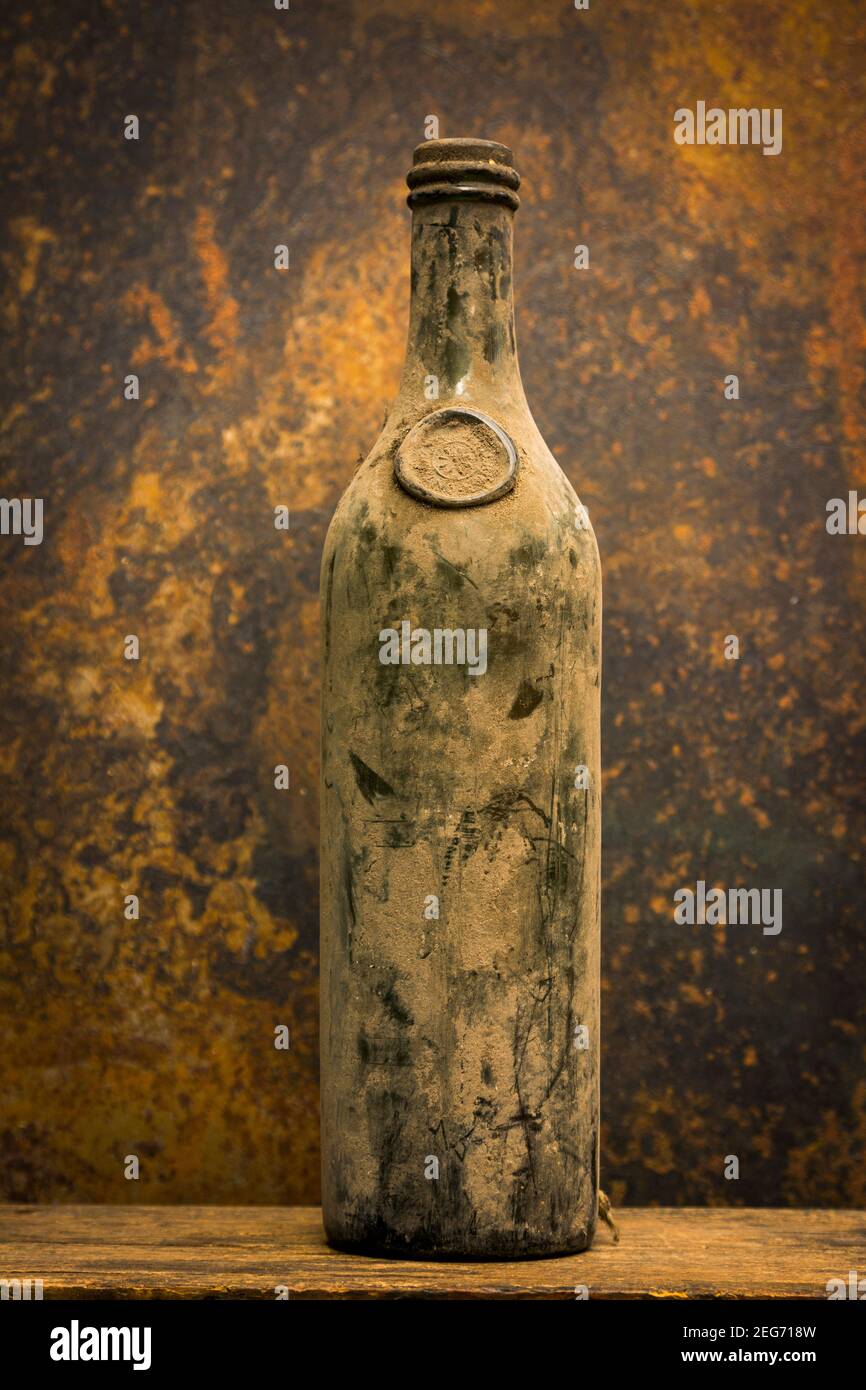 Rustic vintage bottle with weathered texture against a warm, textured ...