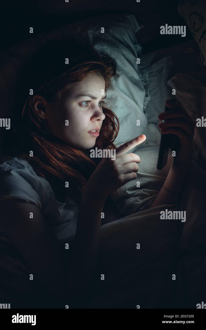 woman with a phone in her hands at night before bedtime emotions ...