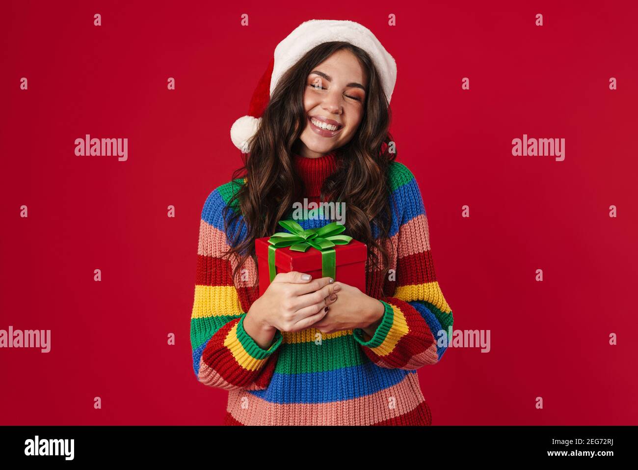 Beautiful happy girl in Santa Claus hat posing with Christmas gift ...