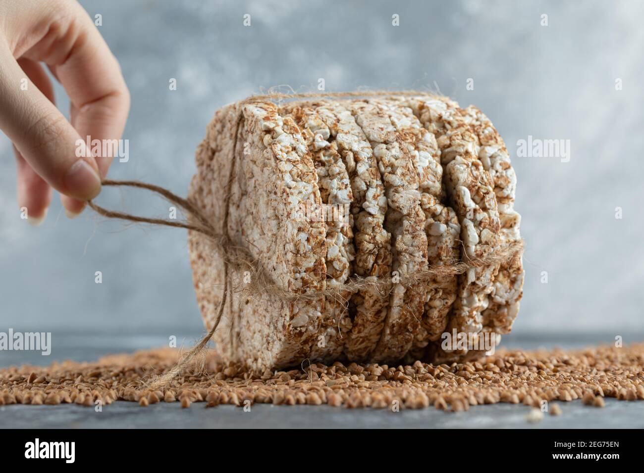 Female hands holding rope of rice cake on marble background Stock Photo ...