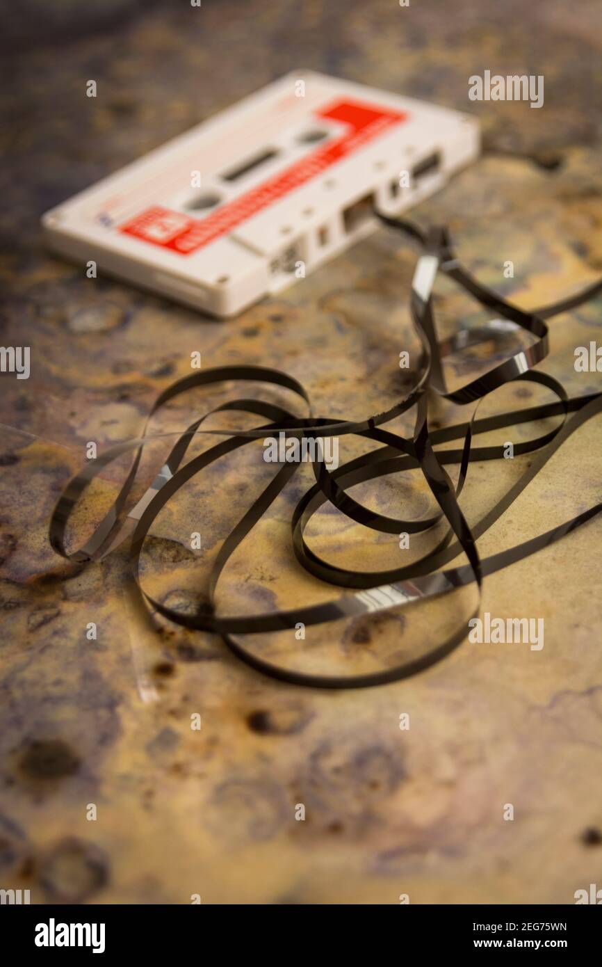 Old cassette tape with tangled tape lying on a textured surface ...
