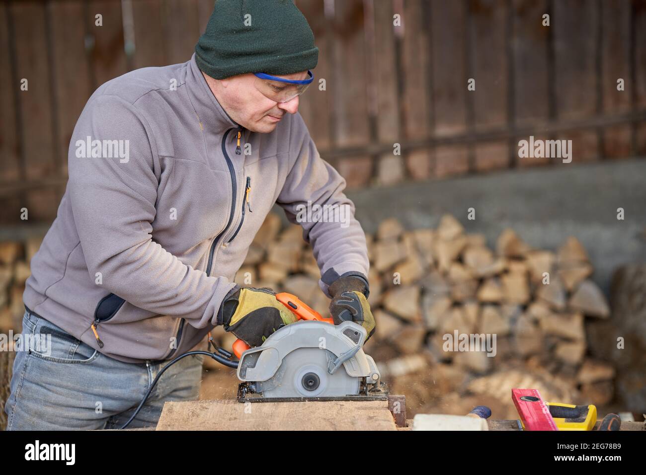 Carpenter using a hand circular saw with laser to cut a walnut board ...