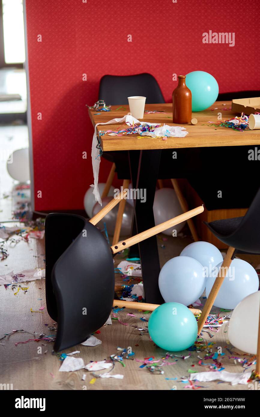 After party chaos, messy in livving room at home, table with pizza and ...