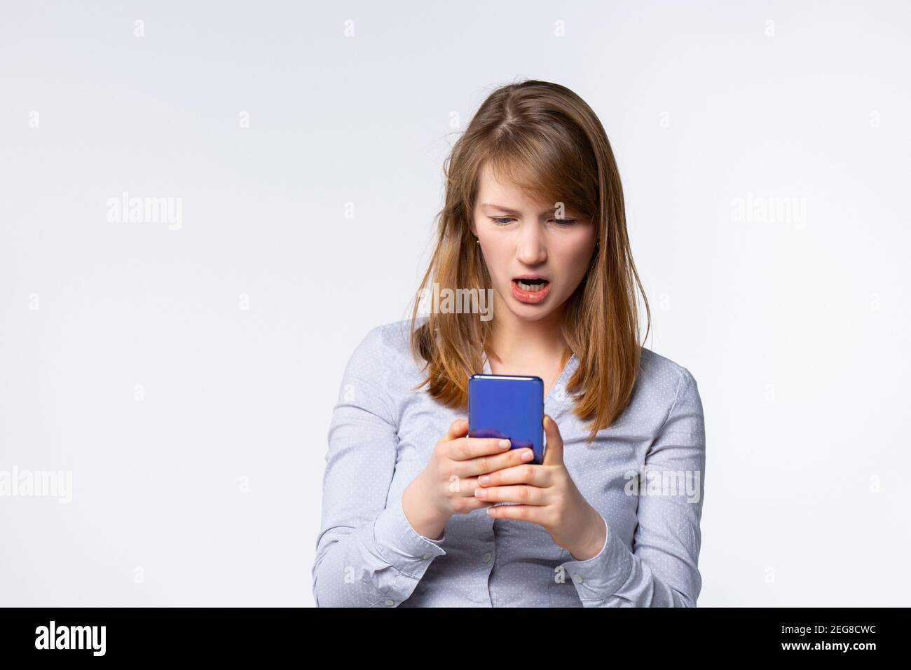 Angry young woman looking at smartphone frustrated by no signal or scam ...