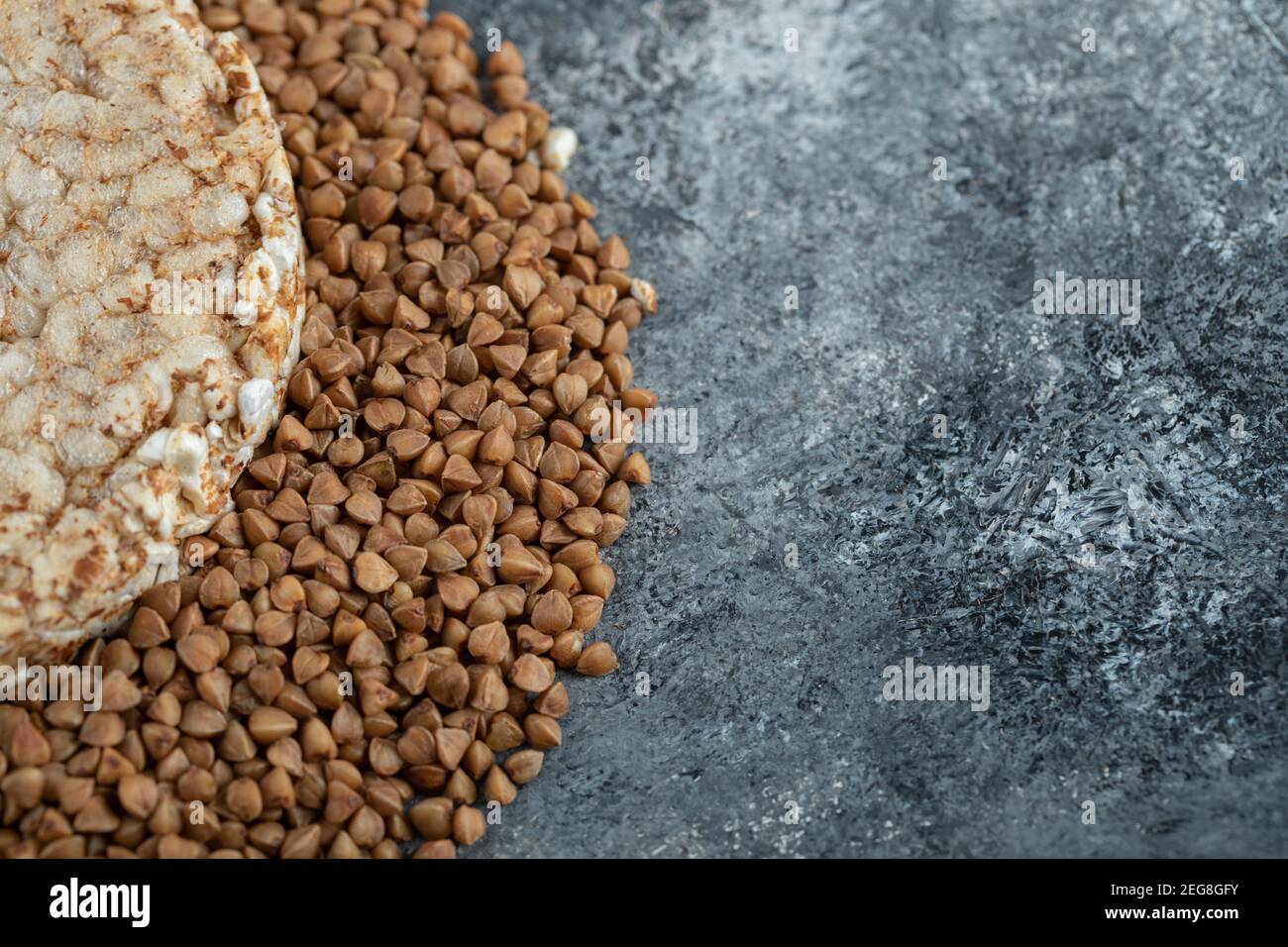 Single rice cake and uncooked buckwheat on marble surface Stock Photo ...