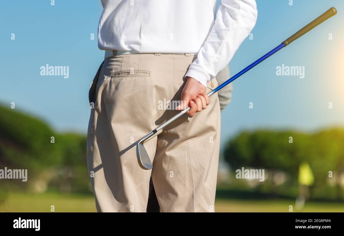On focus shot of back of a golfer holding a club on a green golf field ...