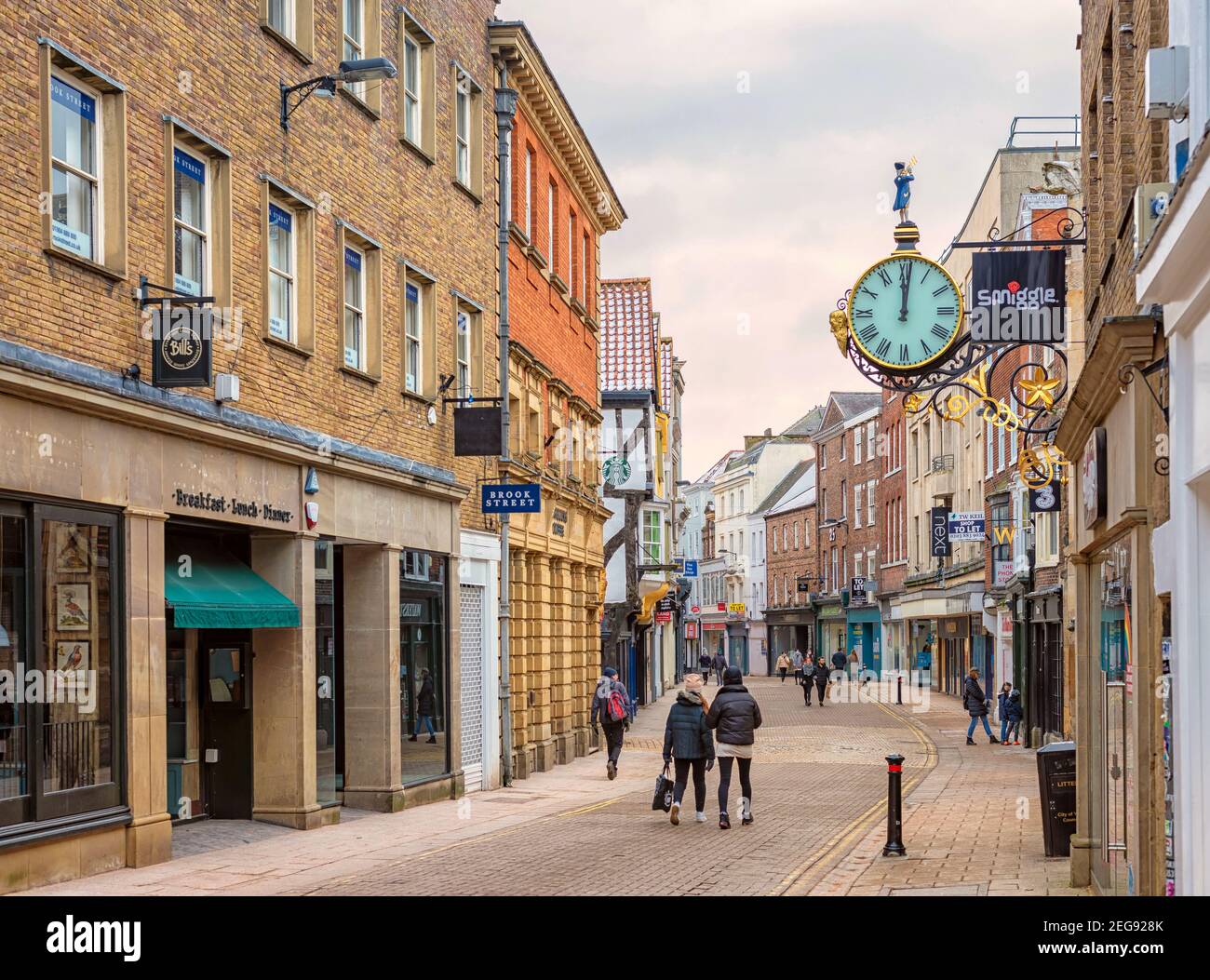A pedestrianised shopping street with an ornate clock in the foreground ...