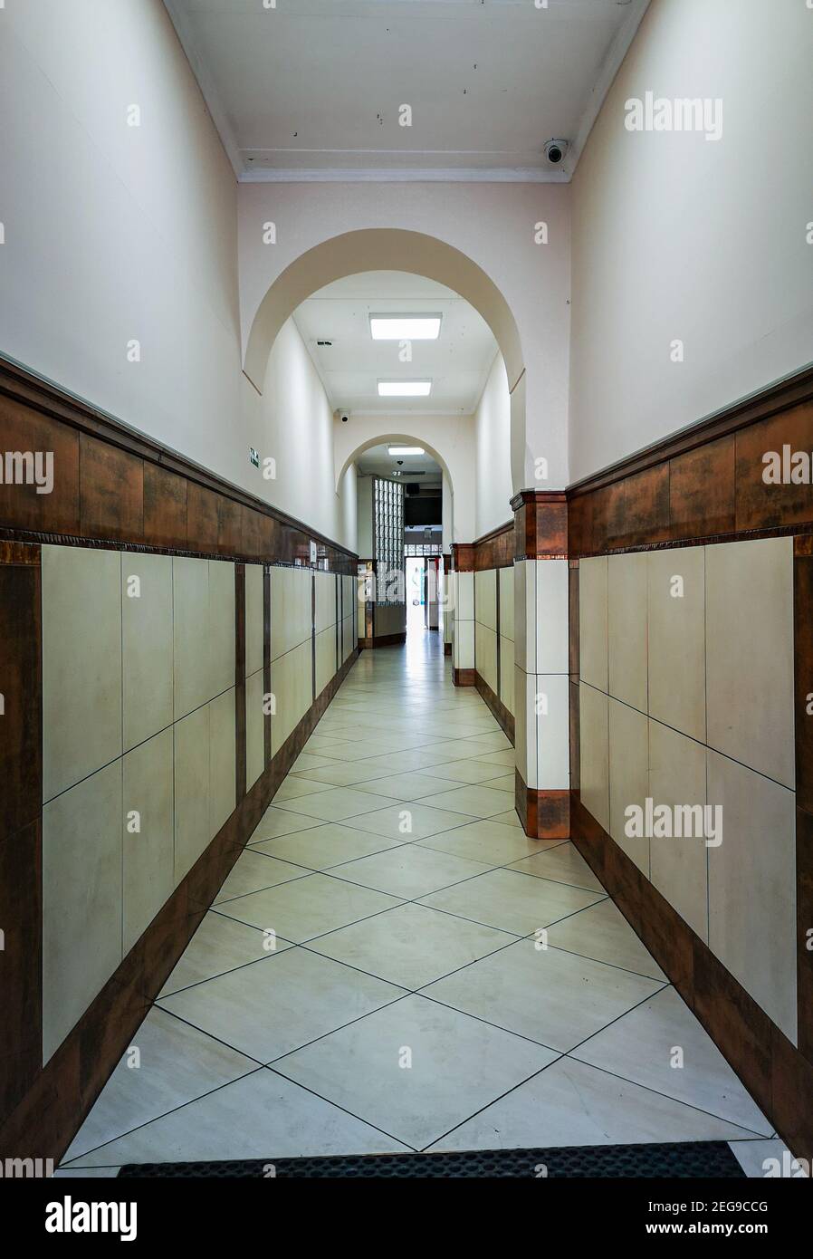 Long light corridor with light and dark tiles and cameras in corners ...