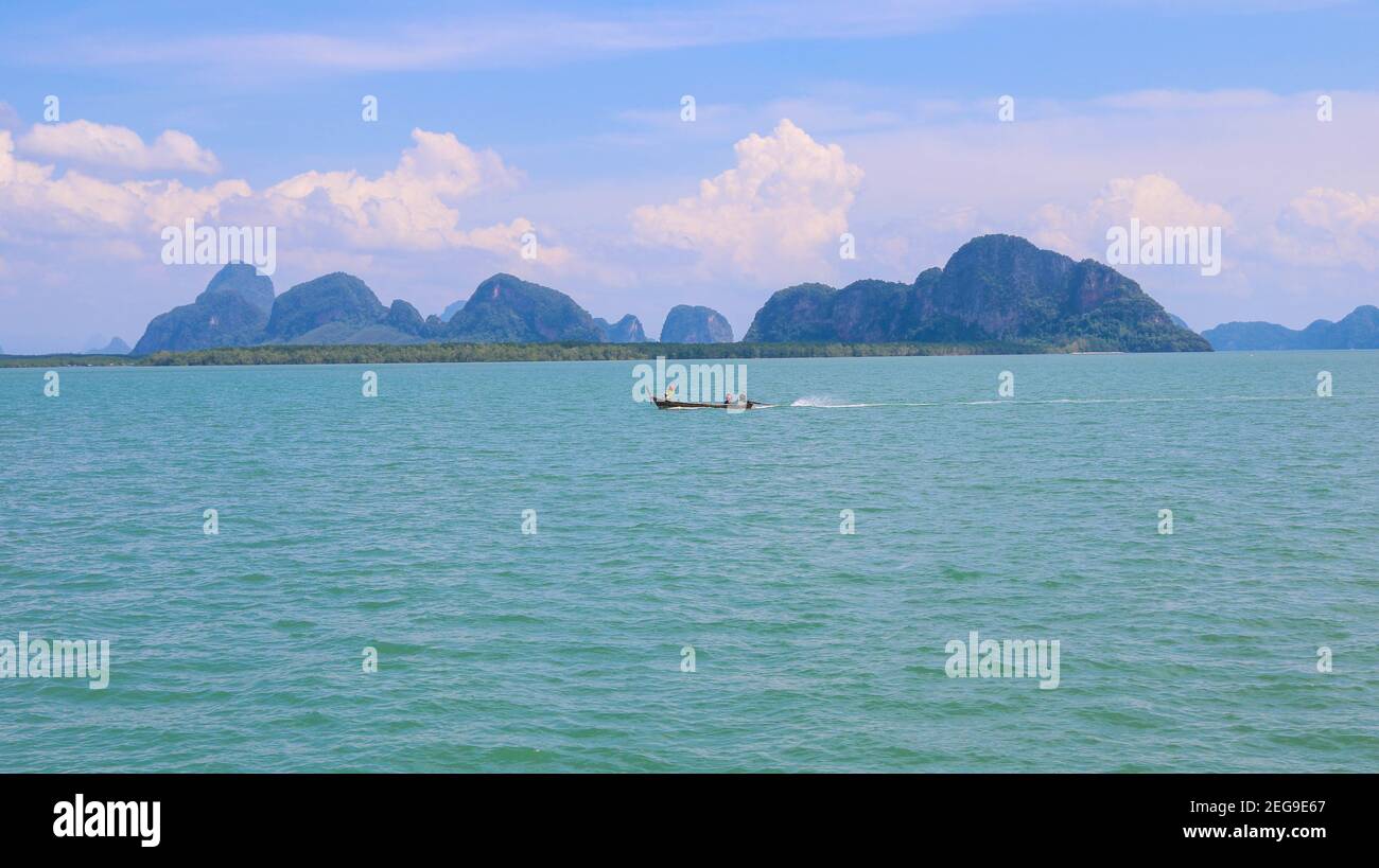 Fishing boat sailing on the wavy sea surrounded by cliffs gleaming ...
