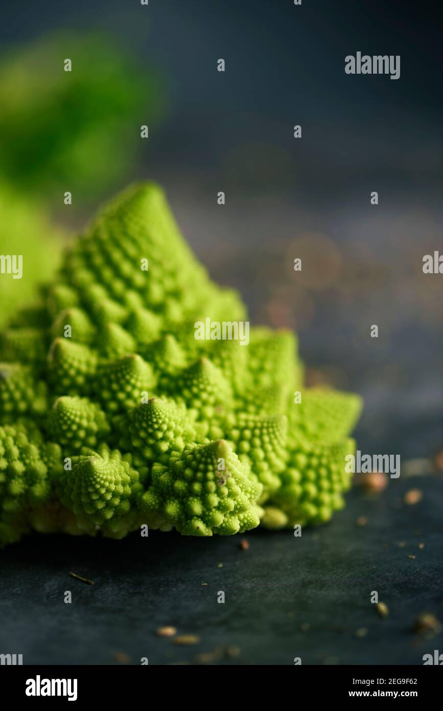 some raw baby romanesco broccoli heads placed on a dark stone surface ...