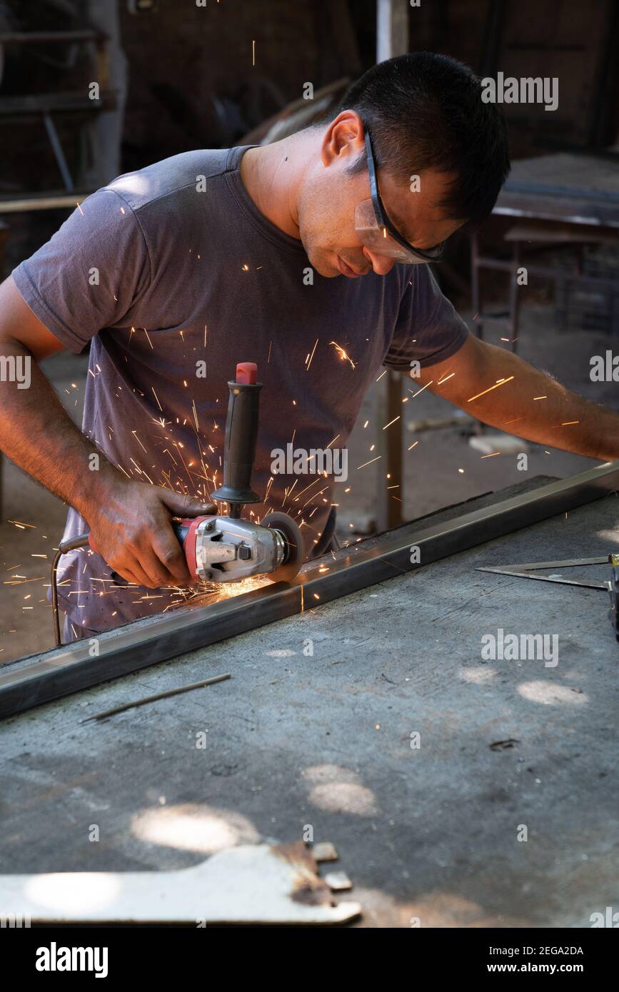 a man working cutting metal bar with a circular electric tool that ...