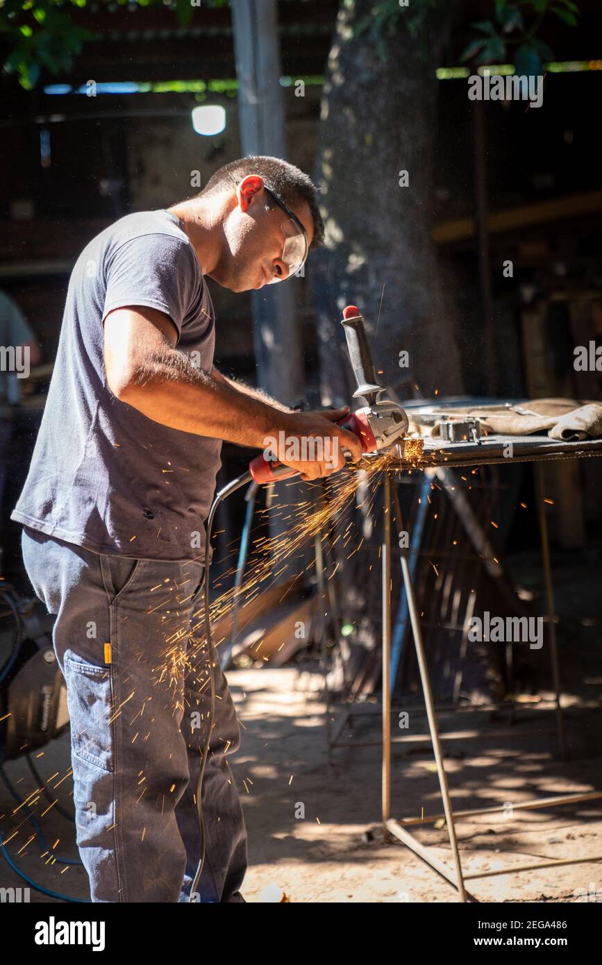 a man working cutting metal bar with a circular electric tool that ...