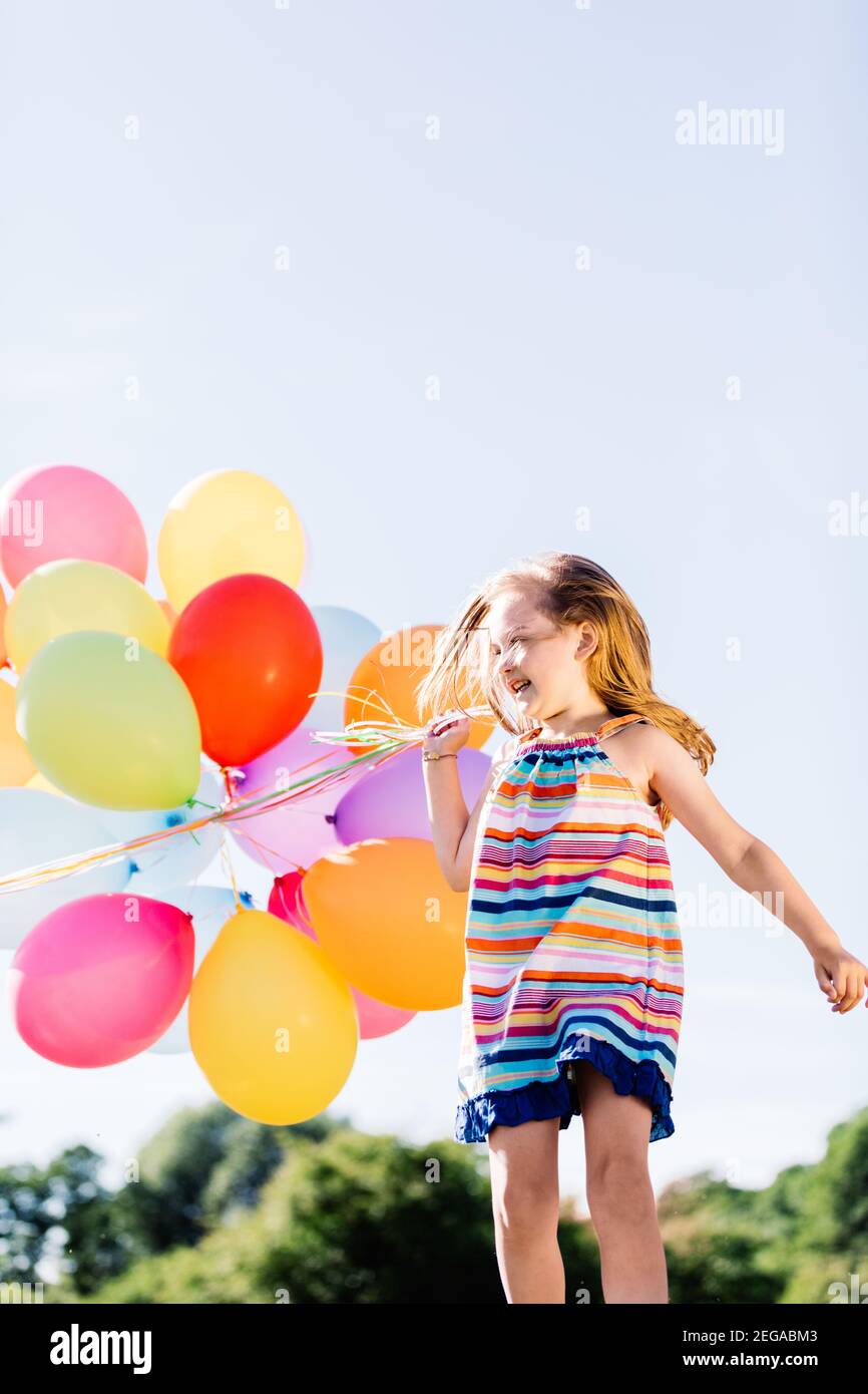 Happy girl running in the park with a bunch of colorful balloons ...