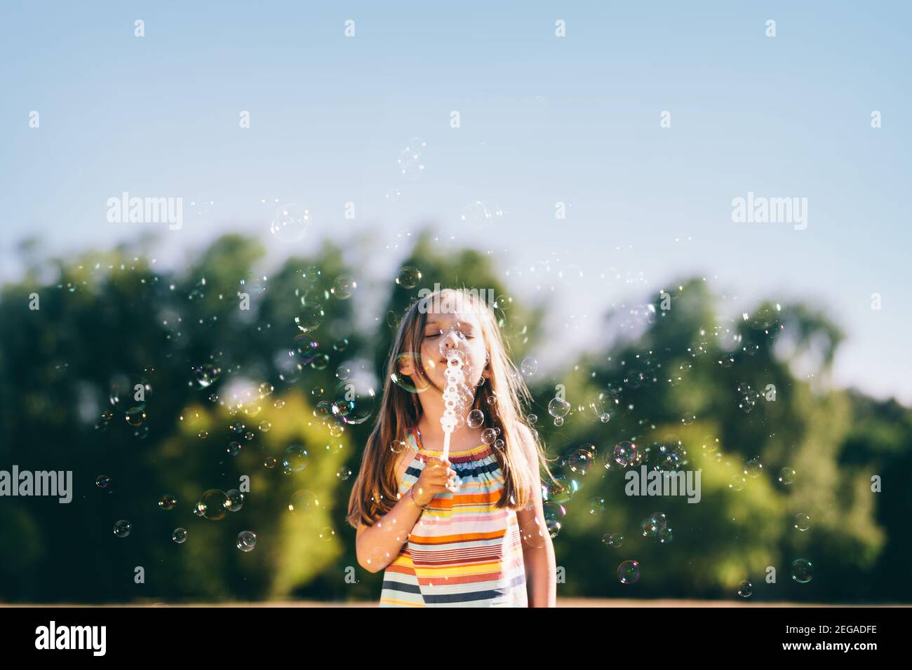 Little girl blowing soap bubbles in the park. Summer outdoor activities ...