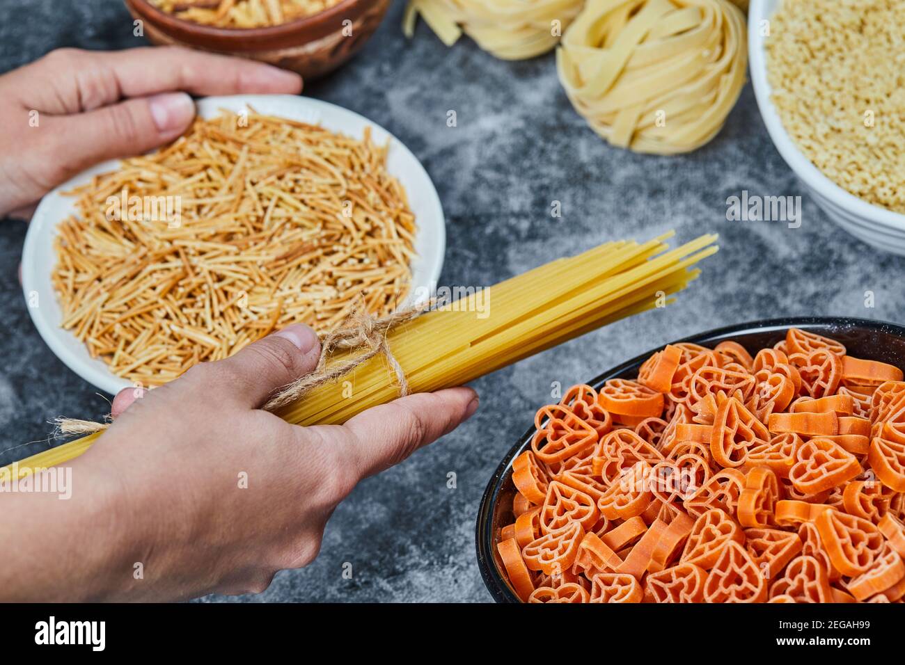Hand holding a bowl of dry pasta with various types of raw pasta Stock ...