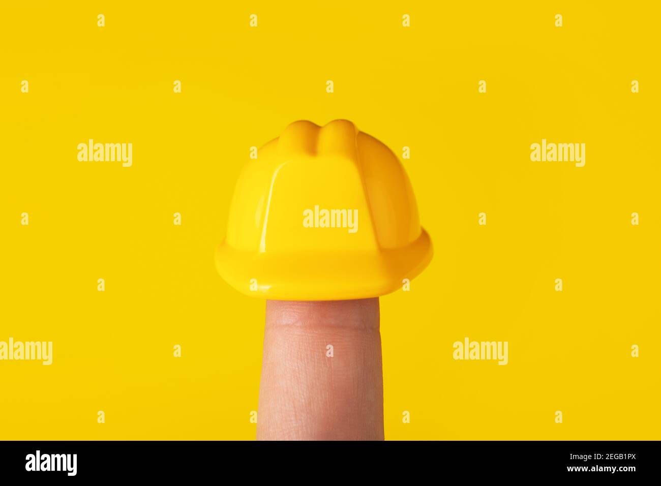 helmet on finger over yellow background, construction hard hat for head ...