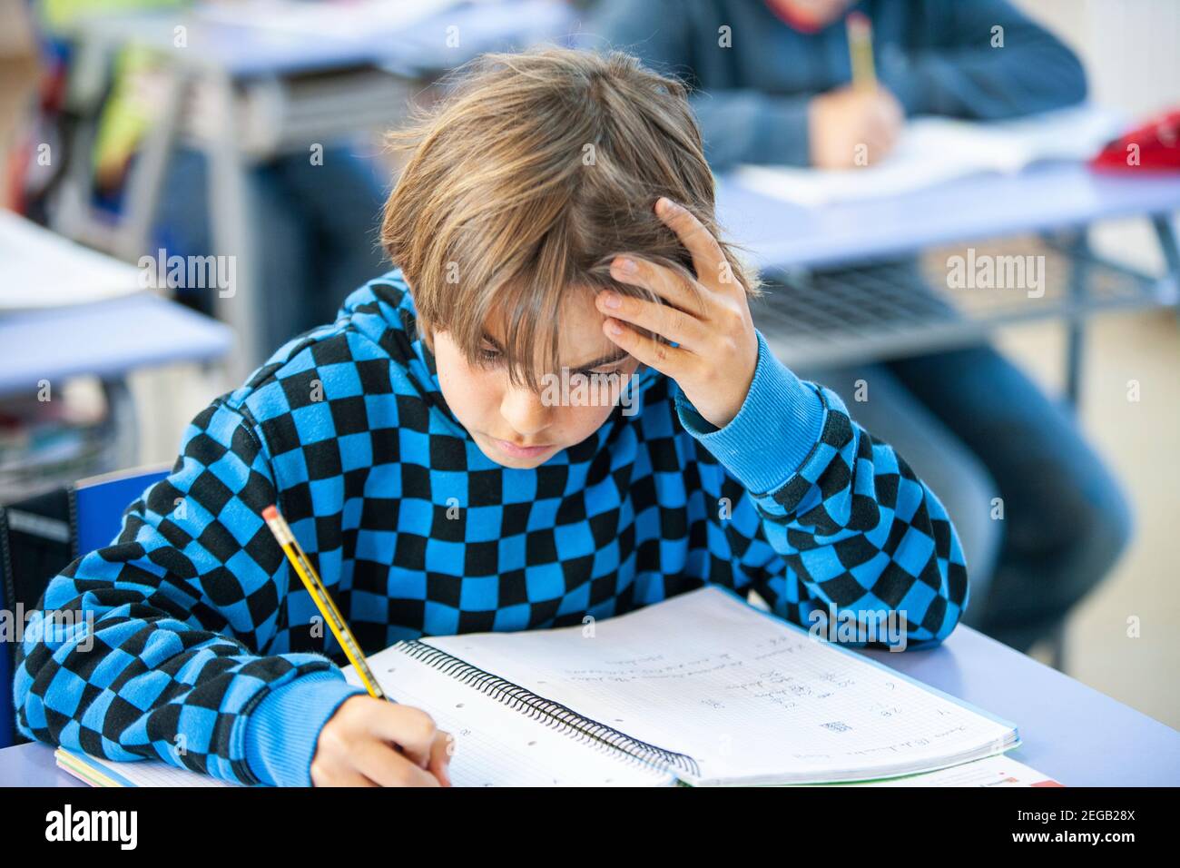 Young boy writing in school classroom Stock Photo - Alamy