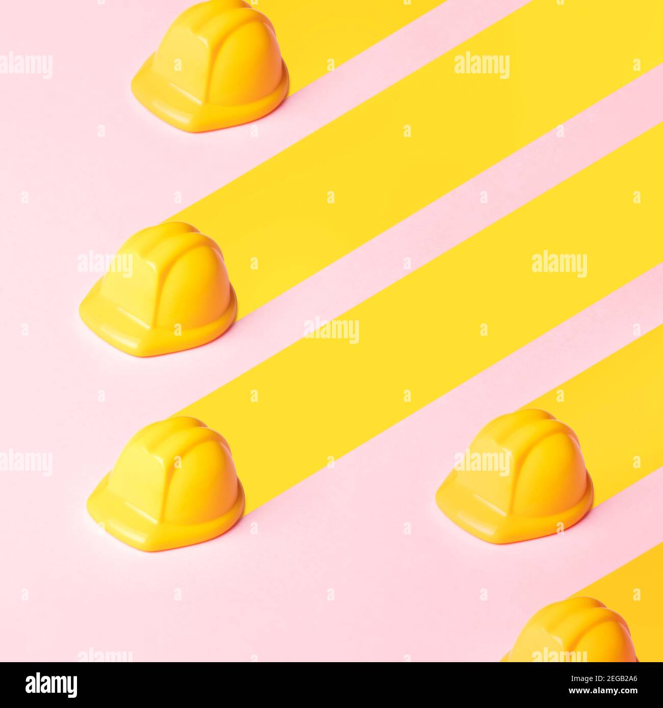 Safety yellow helmets over pink background, construction with ...