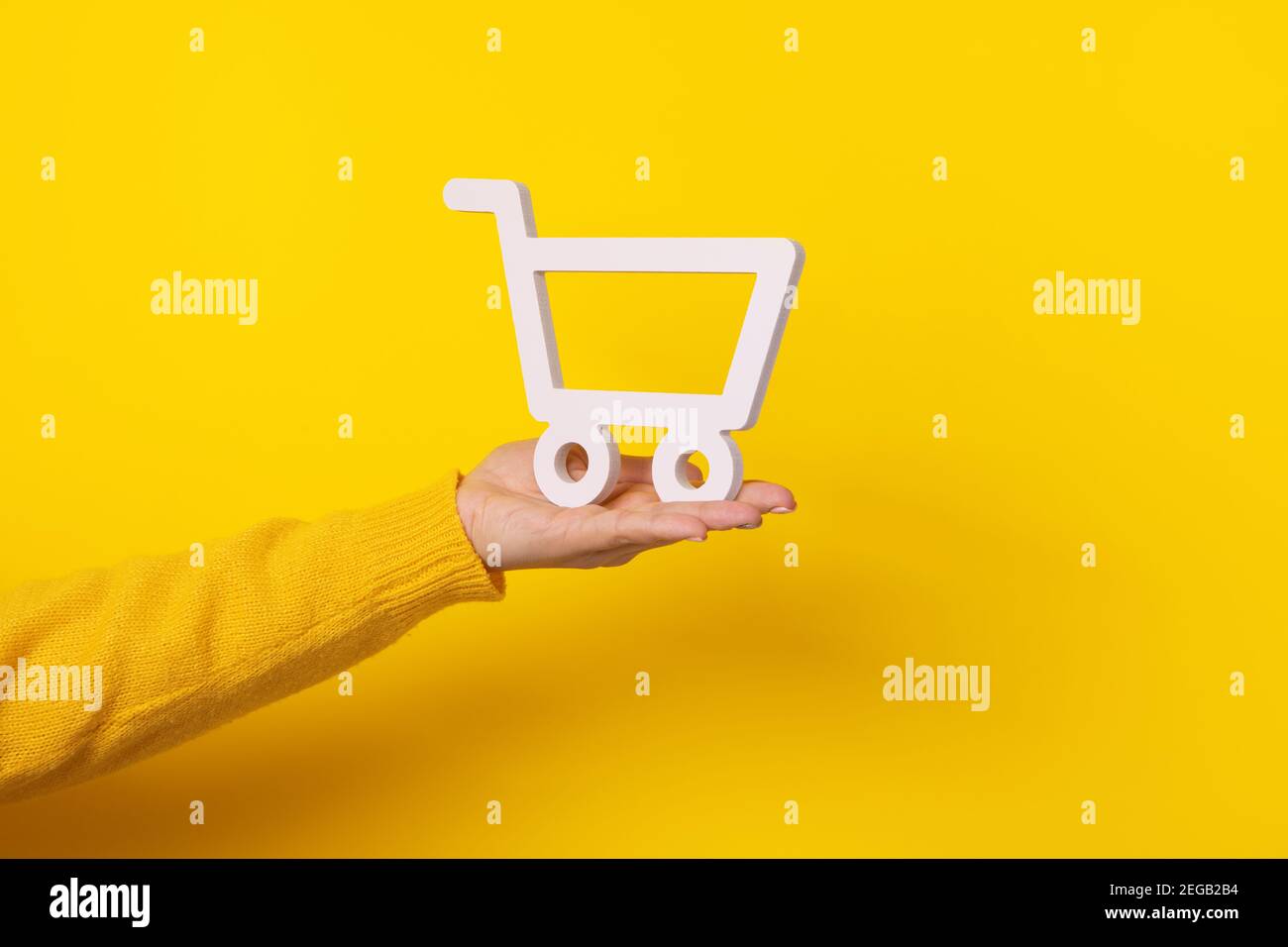 shopping cart on hand over yellow background Stock Photo - Alamy