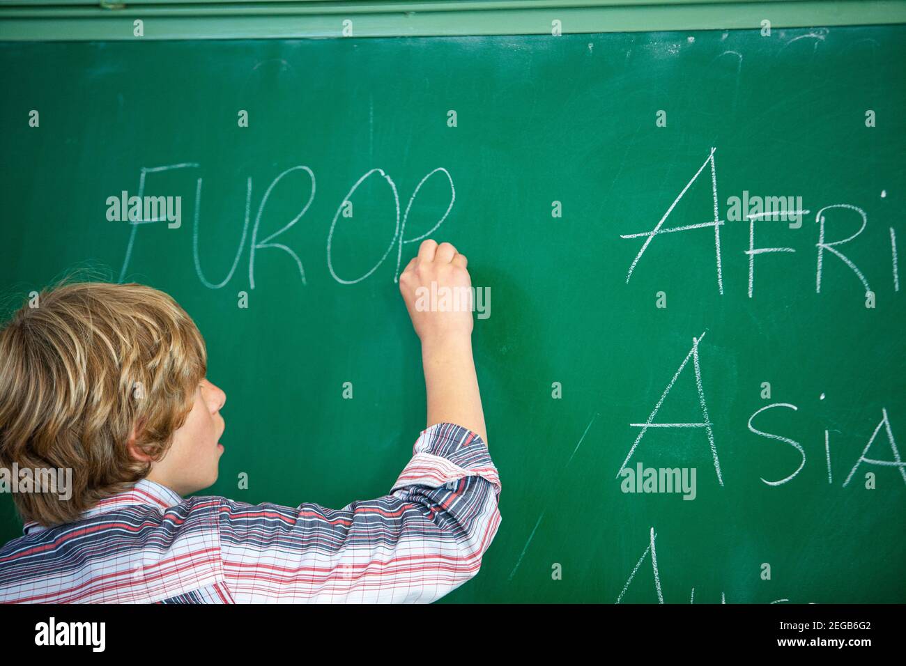 Young boy writing on the chalk board in a school classroom Stock Photo ...