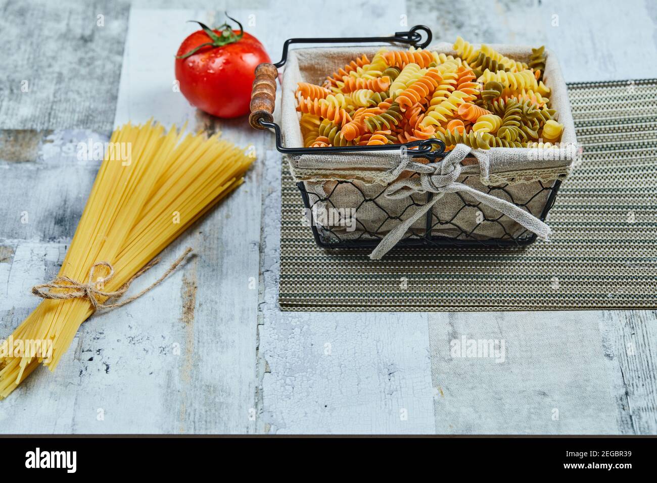 Basket of colorful uncooked pasta, spaghetti and vegetables on a blue ...