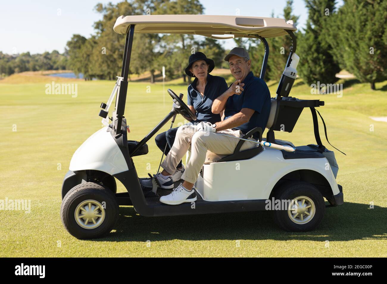 Caucasian senior man and woman driving golf buggy on golf course ...