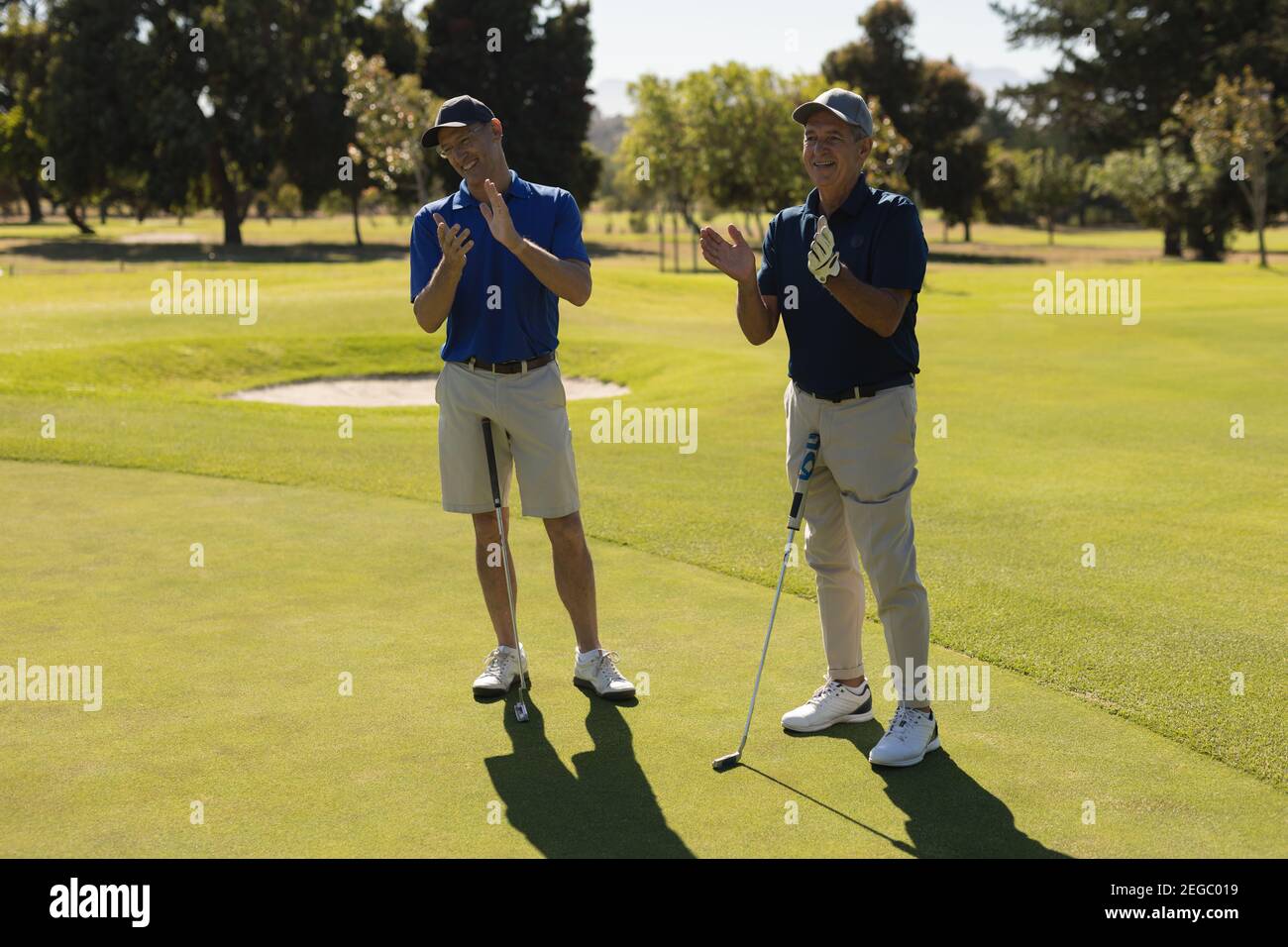 Two caucasian senior men holding golf clubs and clapping Stock Photo ...