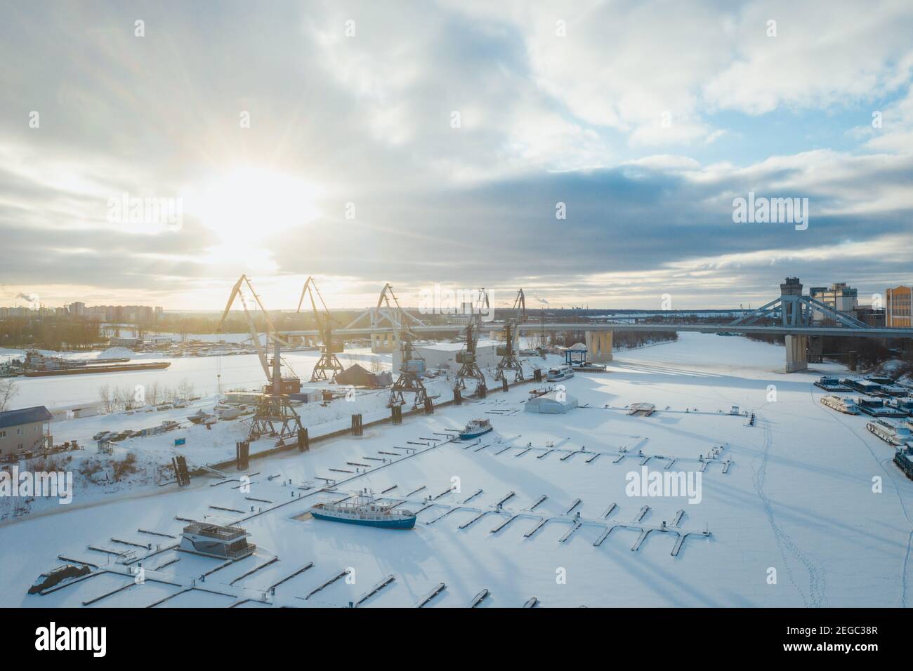 Frozen river with far bridge and harbor cranes Stock Photo - Alamy