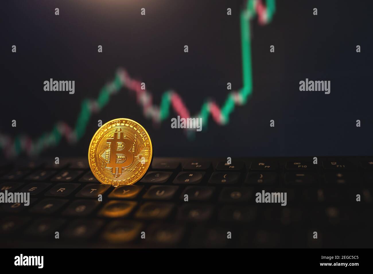 Gold shining Bitcoin coin on keyboard with dark raising graph ...