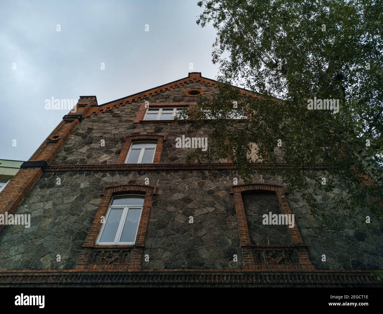 Upward view to old house made by stone and brick with window frame ...